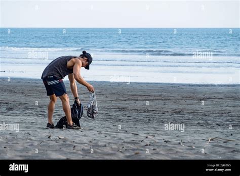 Young Man Picking Up Trash On The Beach Save The Planet Copy Space