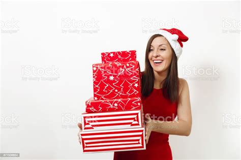 매력적인 미소와 아름 다운 백인 젊은 행복 한 여자 입고 빨간 드레스와 흰색 바탕에 선물 상자를 들고 크리스마스 모자 현재 격리와 산타 소녀입니다 새 해 휴일 2018 개념