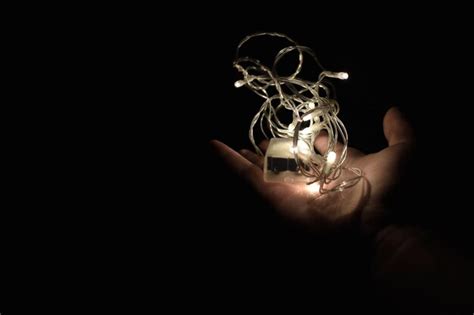 Premium Photo Cropped Hand Holding Illuminated String Light Against