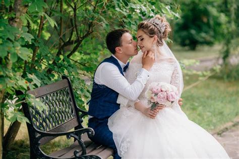 The Bride Sits In The Arms Of Her Fiance Who Gently Holds Her Chin And