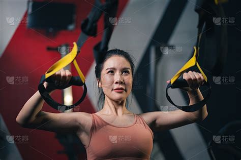 年轻的亚洲女运动员在健身馆锻炼trx肩带