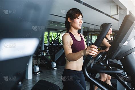 年轻女性和她的朋友在健身房里做运动自行车。