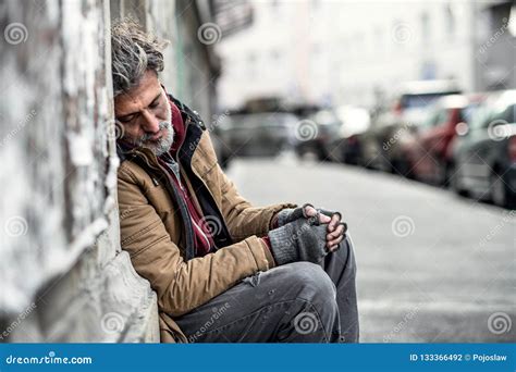 Homeless Beggar Man Sitting Outdoors In City Asking For Money Donation
