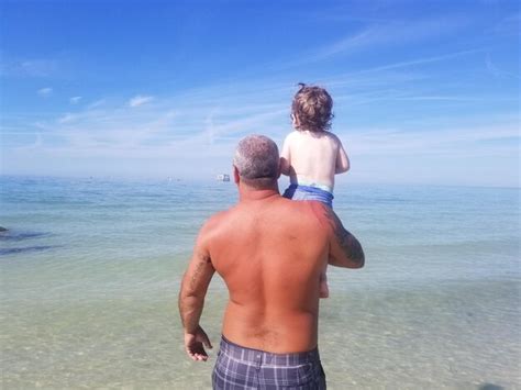 Premium Photo Rear View Of Shirtless Man With Son Standing In Sea