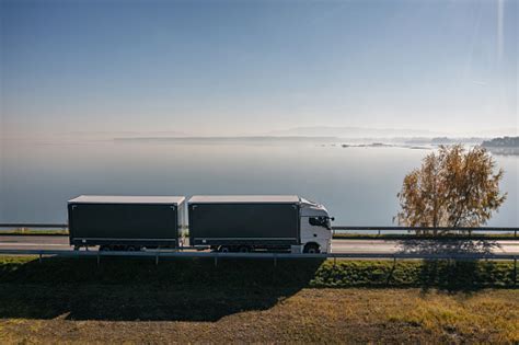 트럭은 가을에 도로를 간다 자동차 운송 회색 색깔에 있는 세미트레일러를 가진 트럭 가을에는 수송 트럭이 호수 옆에서 운전합니다 0명에 대한 스톡 사진 및 기타 이미지