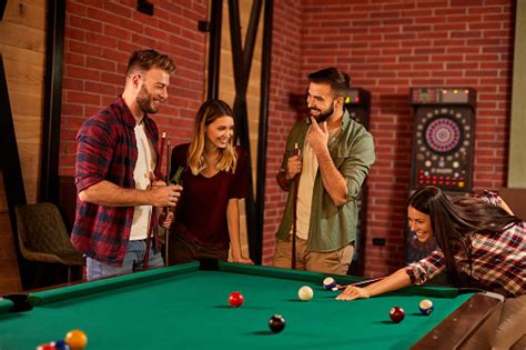 Group Of Friends Having Fun While Playing Pool In A Local Pool Hall