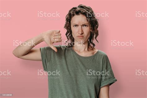 젊은 곱슬 머리 여자 찡그린 얼굴 불쾌 한 제공 엄지 손가락 아래로 제스처 엄지손가락을 아래로에 대한 스톡 사진 및 기타 이미지