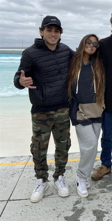 Three People Standing Next To Each Other In Front Of The Ocean