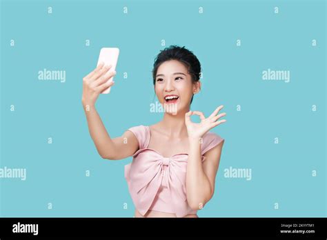 Happy Young Woman Making Silly Faces While Taking Selfie On Smartphone