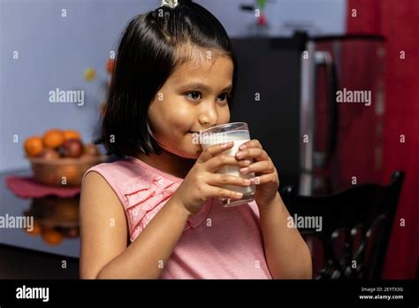 Side Face Of A Cute Little Indian Asian Girl Drinking Milk From Glass