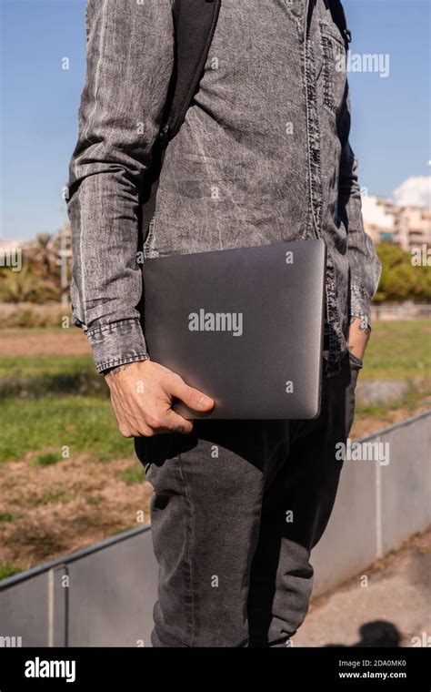 Side View Of Crop Unrecognizable Male With Hand In Pocket Holding Netbook For Working Outdoors