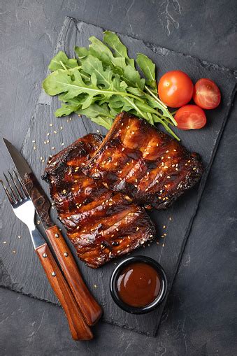 돼지 갈비 바베 큐 소스 구이 Arugula의 침대에 꿀에 Caramelized 어두운 콘크리트 바탕에 신청 위한 나무 보드에