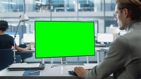 크로마 키 그린 스크린 모의 디스플레이와 데스크톱 컴퓨터에서 작업 하는 사업가의 어깨 샷을 통해 닫습니다 키보드와 마우스를 사용하여 디지털 프로젝트 관리자 타이핑 데이터