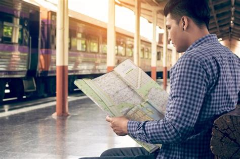 Premium Photo Man Holding Map While Sitting At Railroad Station Platform