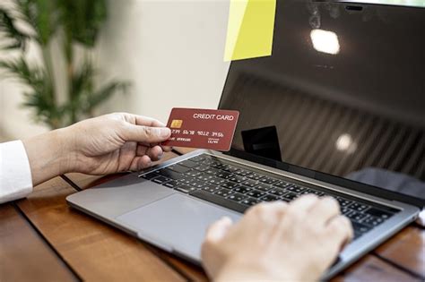Premium Photo A Man Holds A Credit Card And Uses A Laptop He Is Filling Out Credit Card