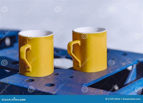 Two Yellow Mugs With A Hot Drink On A Metal Structure On A Winter Day