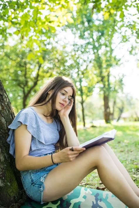 Young Woman Sitting And Reading Her Favorite Book On A O Green Gras