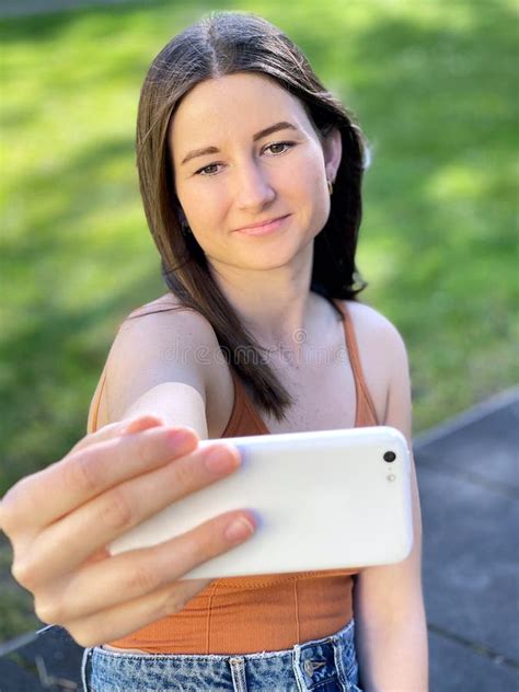 Beautiful Young Woman Outdoors In Park Is Taking A Selfie With Her