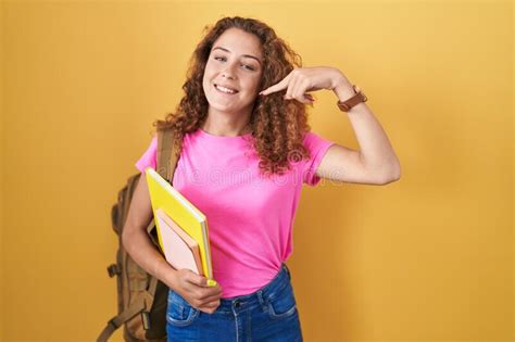 Young Caucasian Woman Wearing Student Backpack And Holding Books
