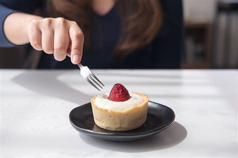 카페에서 흰색 빈티지 나무 테이블에 절단 딸기 치즈 타르트에 포크를 사용 하는 여자의 근접 촬영 이미지 건강하지 못한 생활방식에
