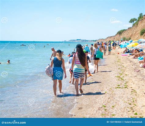Teenagers Walking Along The Seashore Along The Water`s Edge To The