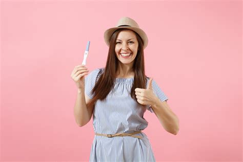 파란 드레스에 흥분된 행복 한 여자 모자 잡고 손 임신 테스트 분홍색 바탕에 고립 된 보고 의료 의료 부인과 임신 임신 출산