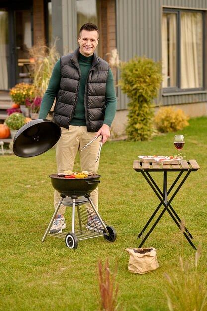 Premium Photo Cheerful Man Grilling Veggies And The Sausage Outdoors