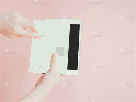 新技术的阅读电子书概念由亚洲妇女拿着并指向她的书和数字平板电脑粉红色的柔和的背景
