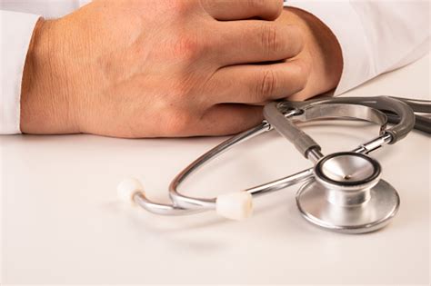 흰 옷을 입은 한 의사가 가슴에 손을 접고 목에 청진기를 걸고 서 있다 클로즈업 간호사에 대한 스톡 사진 및 기타 이미지 간호사 건강 진단 건강관리와 의술 Istock