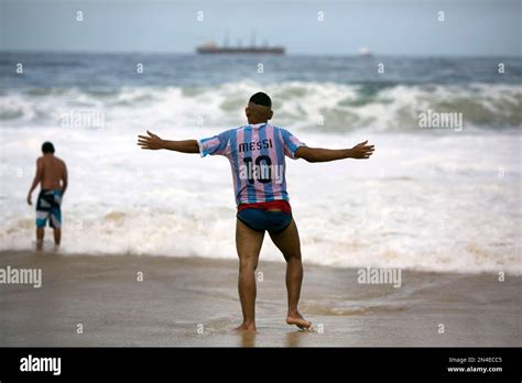 An Argentina Soccer Fan Wearing A Lionel Messi Soccer T Shirt Stands On The Shore Of Copacabana
