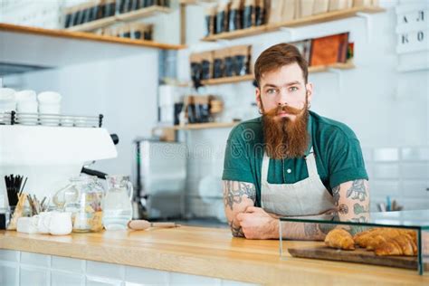 Портрет бородатого мужского Barista стоя в кофейне Стоковое Изображение