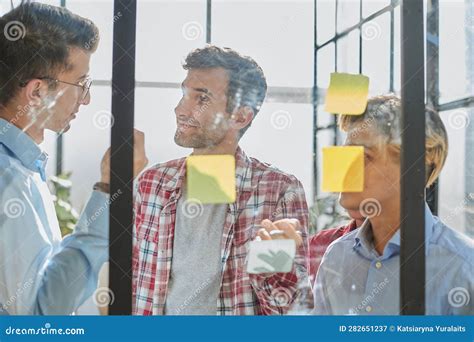 A Group Of Business People Behind A Glass Wall In The Office Sticking