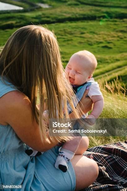 재밌는 아기 행복한 아들을 둔 어머니는 자연 속에서 피크닉을 하며 담요 위에 앉아 있다 해질녘 들판의 푸른 잔디밭에서 즐거운 시간을 보내는 아이 아이는 산에서 놀고 웃고