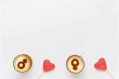 휘핑 우유 거품에 금성과 화성의 상징과 커피 두 컵과 흰색 탁상에 심장 모양의 커플 롤리팝 발렌타인 데이에 로맨틱 한 달콤한 아침 식사를 컨셉 플랫 레이 복사 공간 0명에