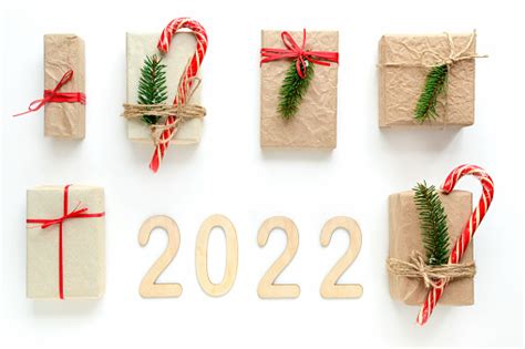 상단 보기 플랫은 빨간색 리본과 주마 실로 묶여 공예 포장프레임 크리스마스 선물의 형태로 흰색 배경에 누워 빨간색 사탕과 가문비 나무 가지로 장식 숫자 2022 0명에 대한