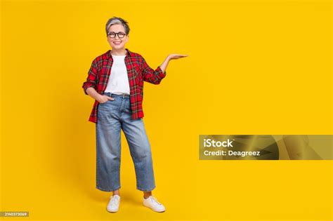 긍정적 인 나이 든 아가씨 팔 손바닥 잡기의 전신 사진은 노란색 배경에 고립 된 빈 공간을 보여줍니다 50 54세에 대한 스톡