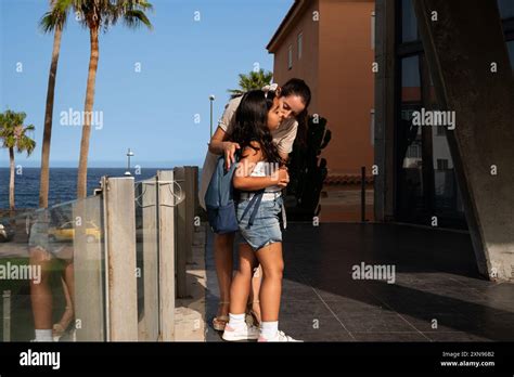 Mother Gives Daughter A Kiss Before Entering School On Her First Day Of