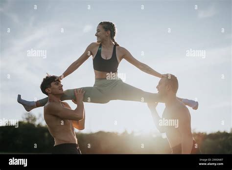 Flexible Woman Performing Front Split Exercise On Friends Shoulders