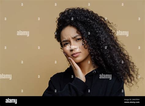 Pensive Woman Touching Her Cheek Curly Hair Black Hoodie Neutral