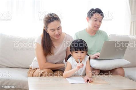 어머니가 숙제를 가르치는 행복한 가족 딸과 아버지가 집 거실 소파에서 노트북으로 일하는 모습 엄마가 아이와 함께 학업 라이프