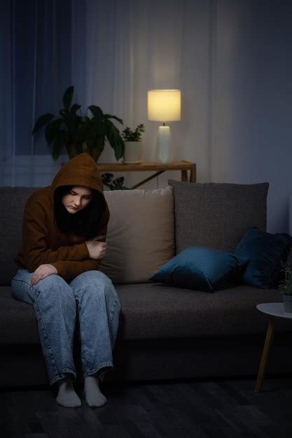Menina adolescente triste sentada no sofá interior à noite Foto Premium
