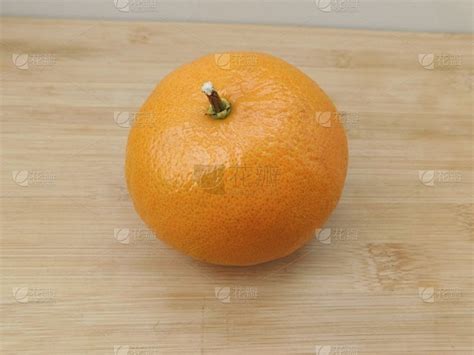 木桌上放着一个新鲜成熟的橘子