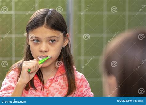 A Girl Brushes Her Teeth With A Toothbrush In The Bathroom A