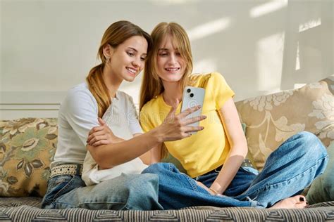Two Cheerful Teenage Girls Having Fun Together With Smartphone Sitting