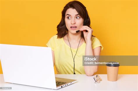노트북 컴퓨터 앞에 앉아 젊은 갈색 머리 여자의 초상화를 닫습니다 헤드셋과 마이크가 있는 여자는 클라이언트와 이야기 인터넷