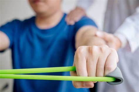 클리닉에서 운동 밴드와 함께 자신의 팔을 스트레칭에 치료를 행사 하는 동안 남성 환자를 돕는 의사 물리 치료사 재활 물리 요법
