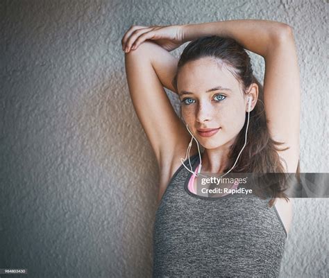 Pretty Girl In Ear Buds By Wall Looks At Camera Smiling High Res Stock