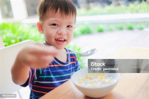 아시아 3 세 유아 소년 아이 착용 줄무늬 티셔츠 사용 숟가락 먹는 시리얼 아침 식사 자기 먹이 먹기에 대한 스톡 사진 및 기타