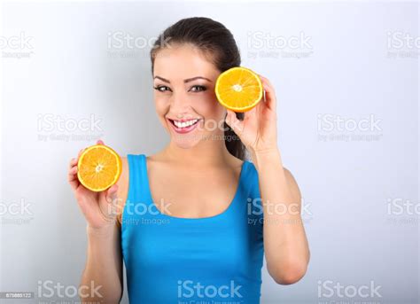 웃 고 이빨 아름 다운 오렌지의 조각 손에 들고 젊은 건강 한 캐주얼 여자를 맞습니다 파란색 배경에 근접 촬영 초상화 갈색 머리에 대한 스톡 사진 및 기타 이미지 Istock