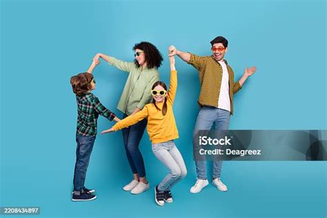 밝은 파란색 배경막을 배경으로 재미있는 제스처를 취하면서 장난기 넘치는 유대감을 즐기는 행복한 4인 가족 10 11세에 대한 스톡 사진 및 기타 이미지 Istock